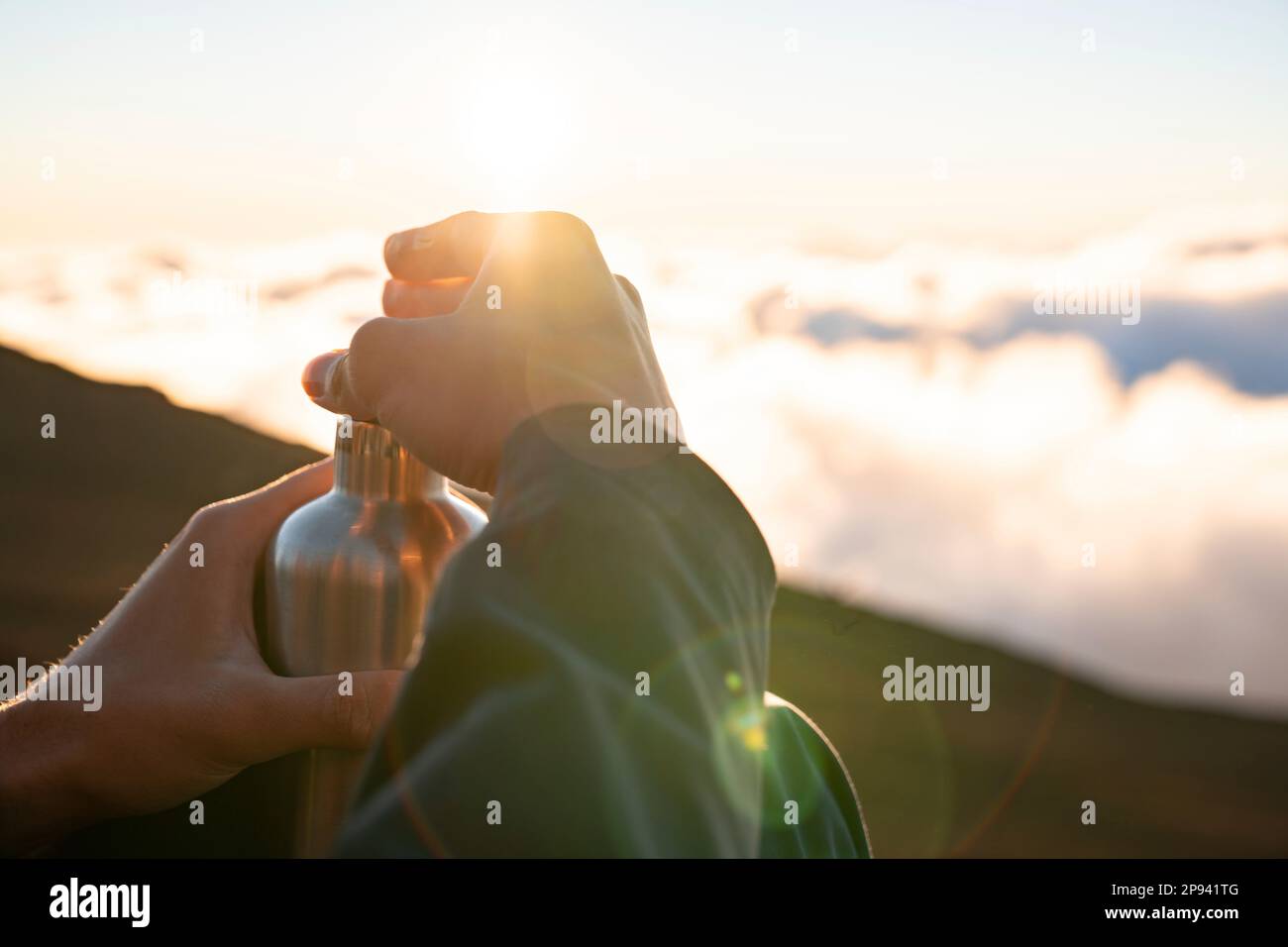 Hands turn up an isokanne at sunset on top of Haleakala, Haleakala ...