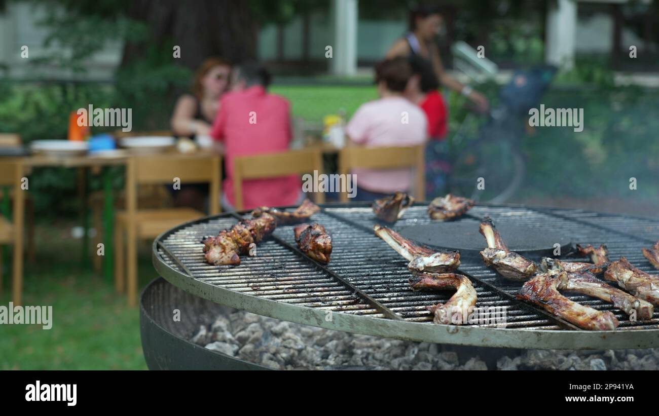 Food cooking on barbecue grill with people in background. Friends and ...