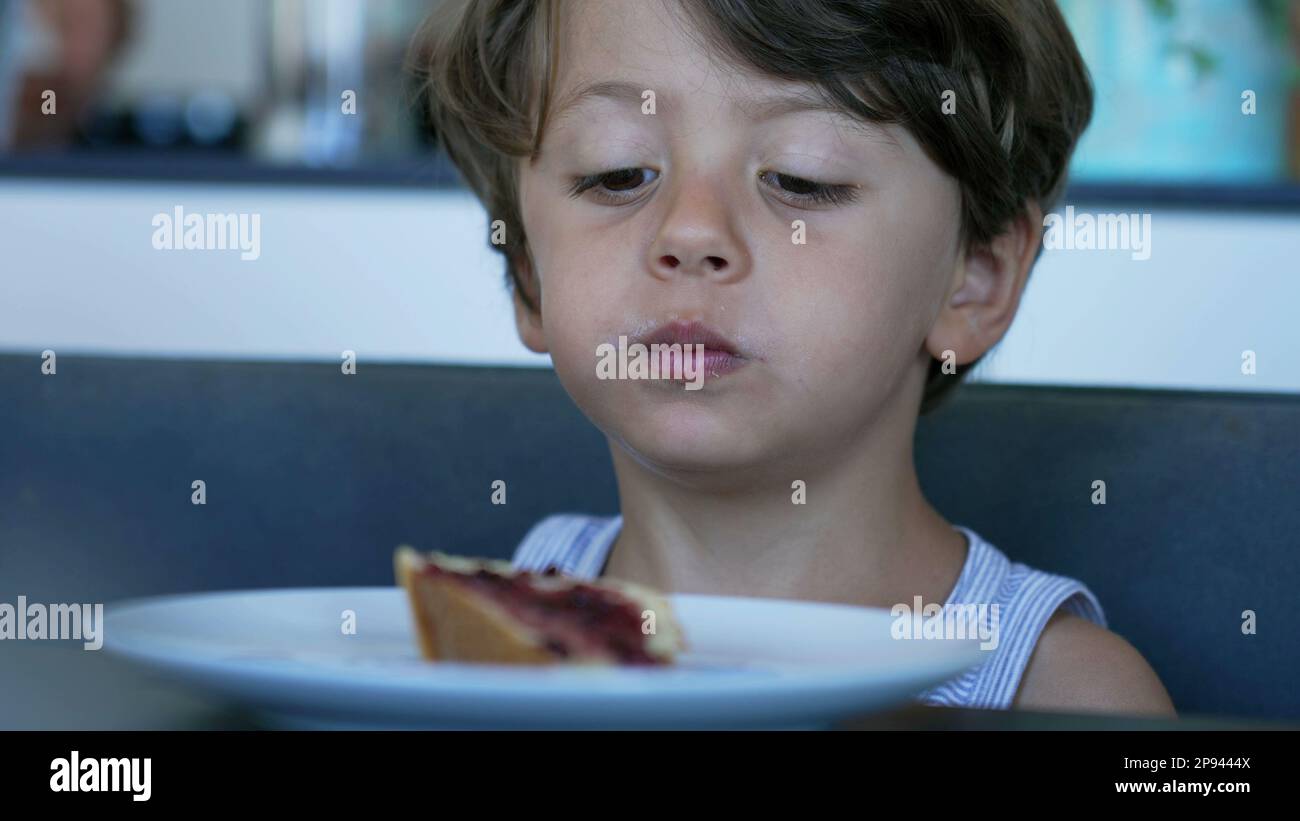 Child eating bread with jelly in morning breafast table. Candid small ...