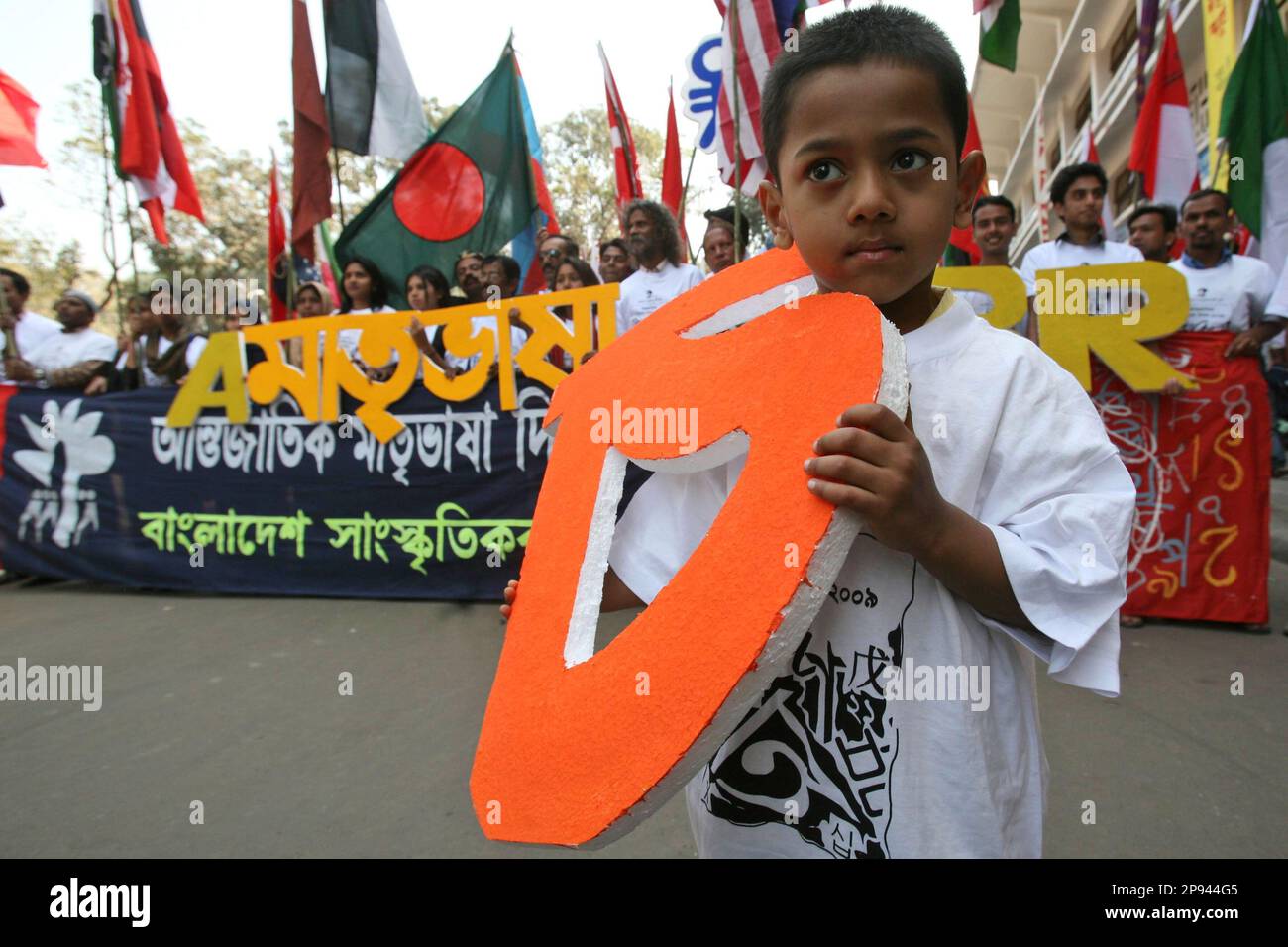 A Bangladeshi boy holds a Bangla alphabet, as cultural workers carry flags of different ...