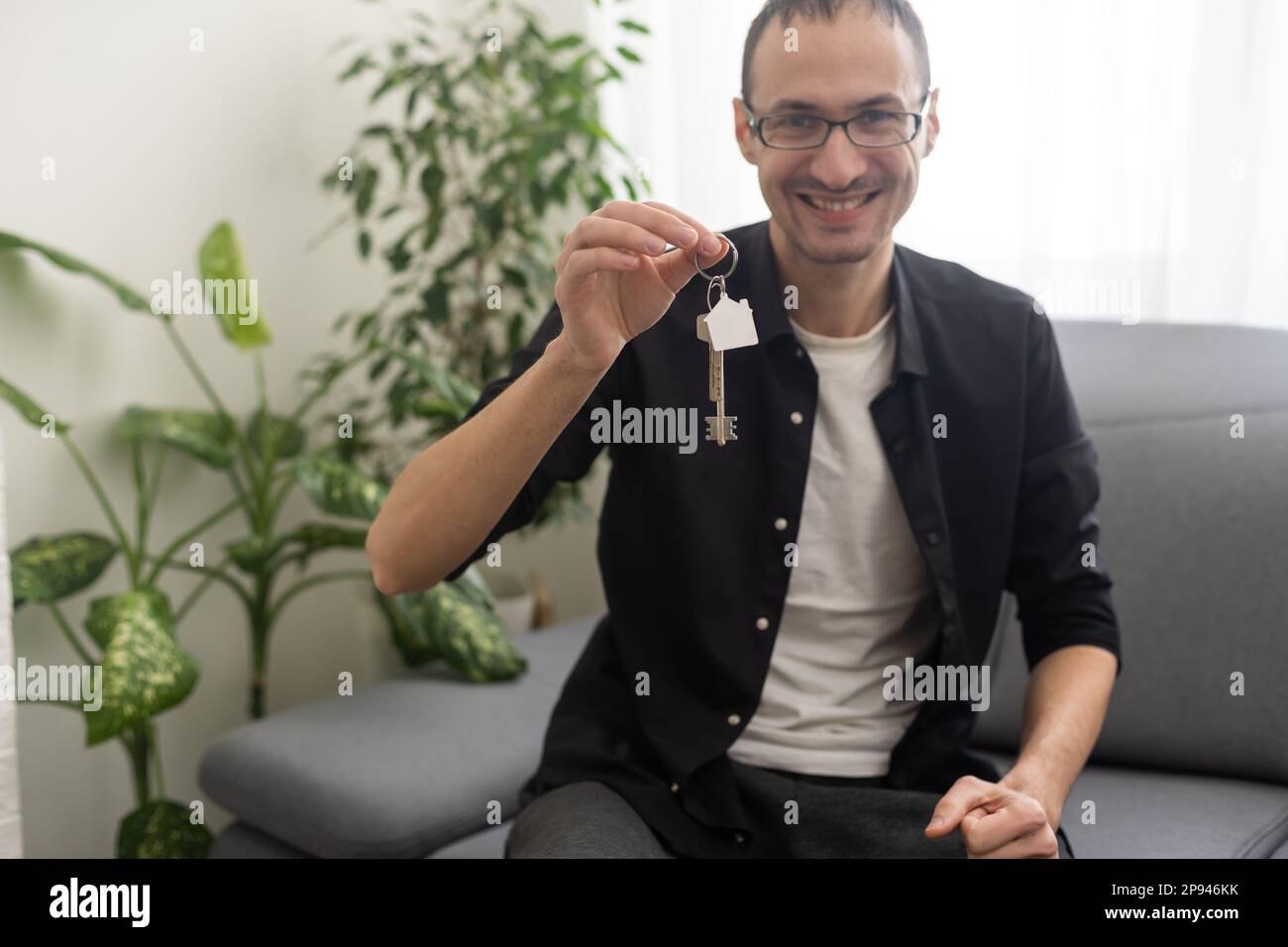 Happy overjoyed guy holding the keys with keychain in form of little ...