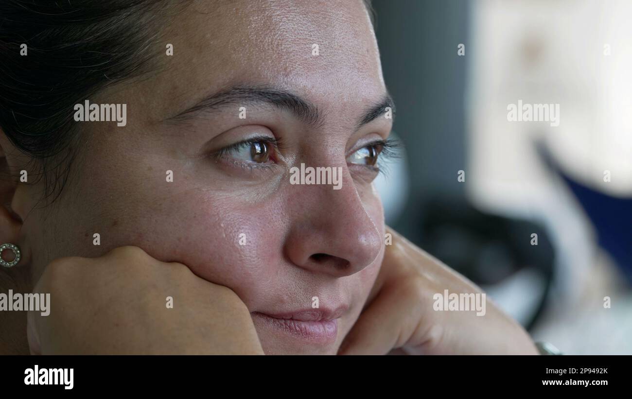 A pensive woman close up face with tearful emotion. Contemplative ...
