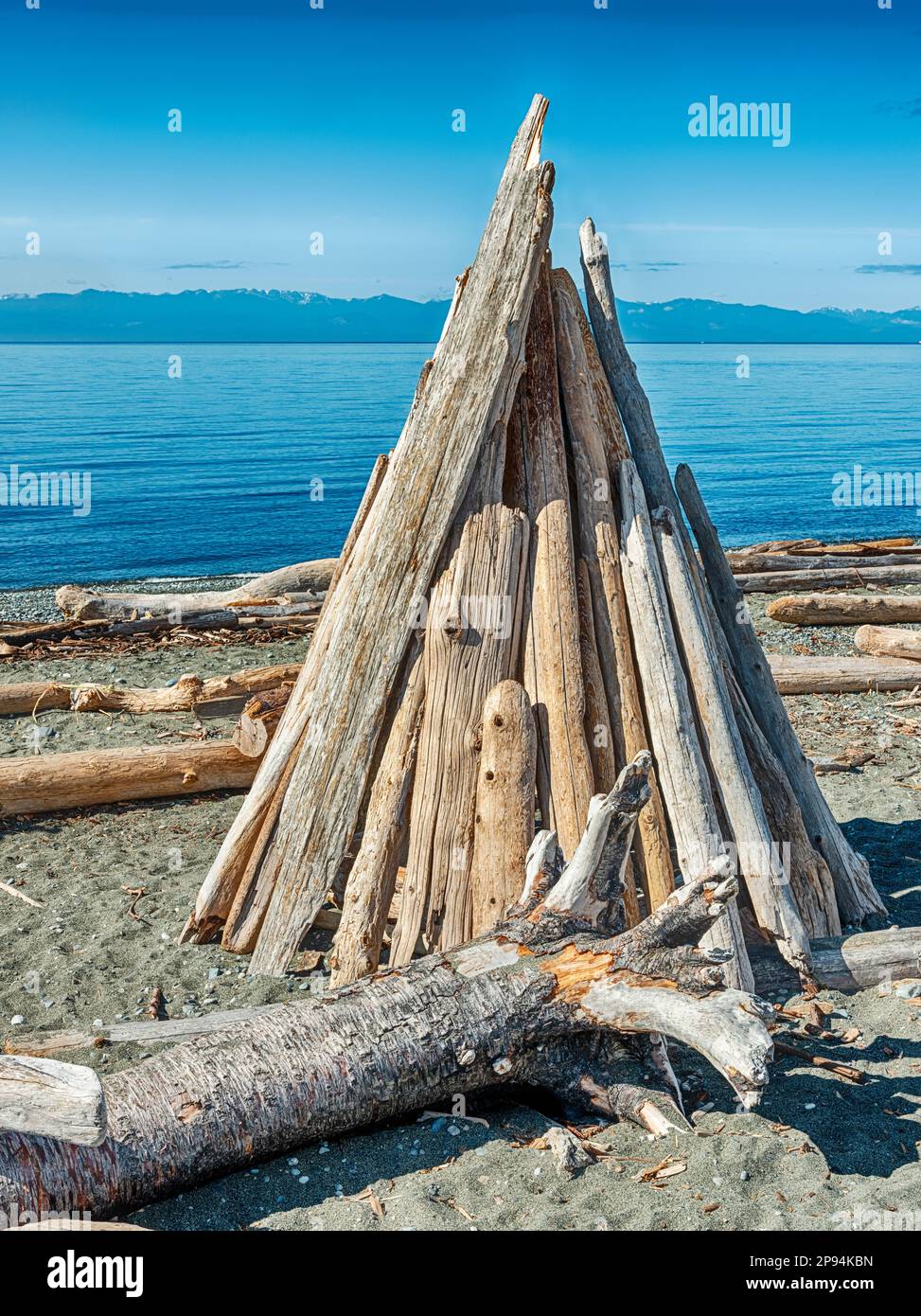 Driftwood logs have been piled up into a simple pyramid form to create ...