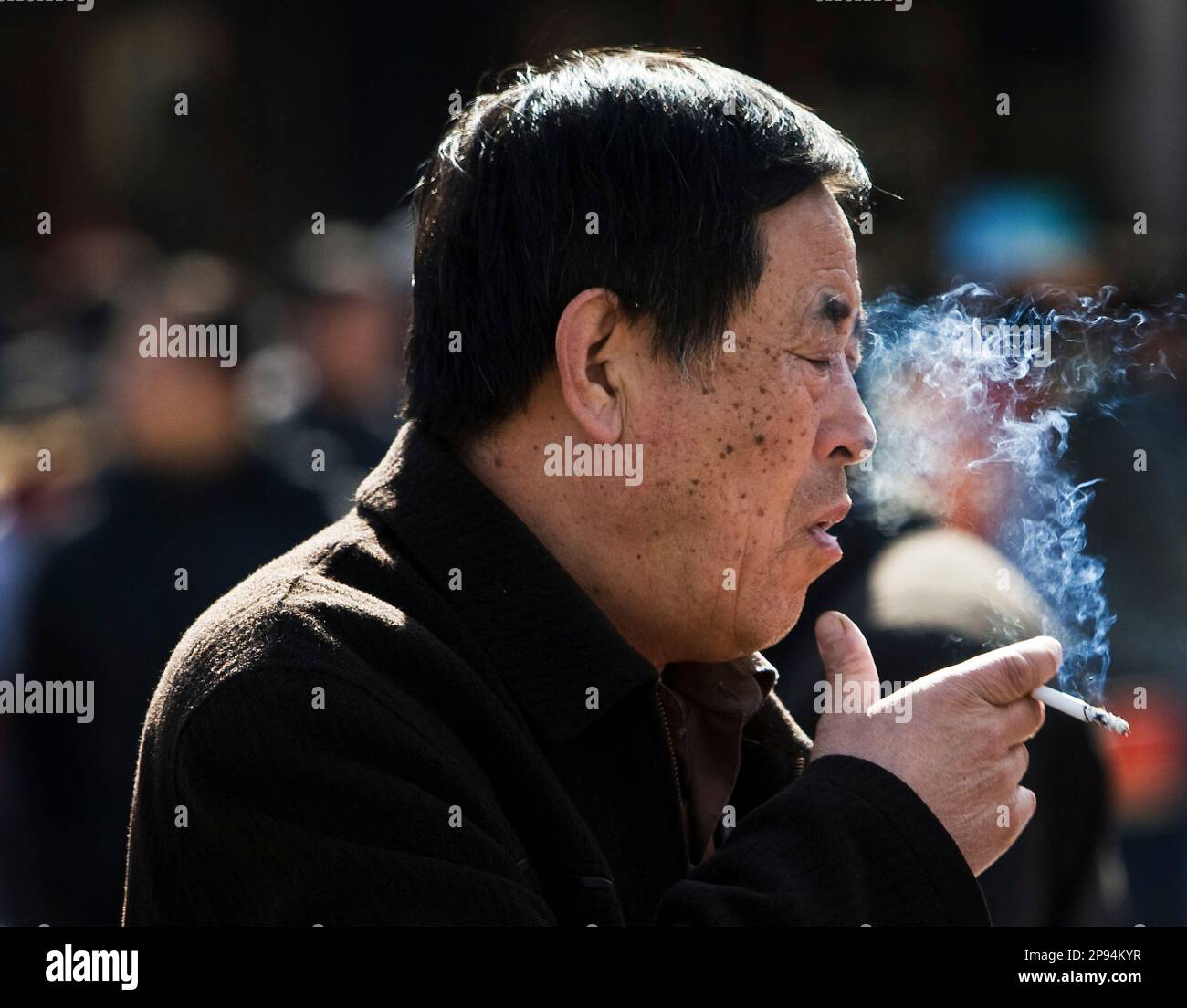 A Chinese man smokes cigarette in the downtown Beijing, China, Monday ...