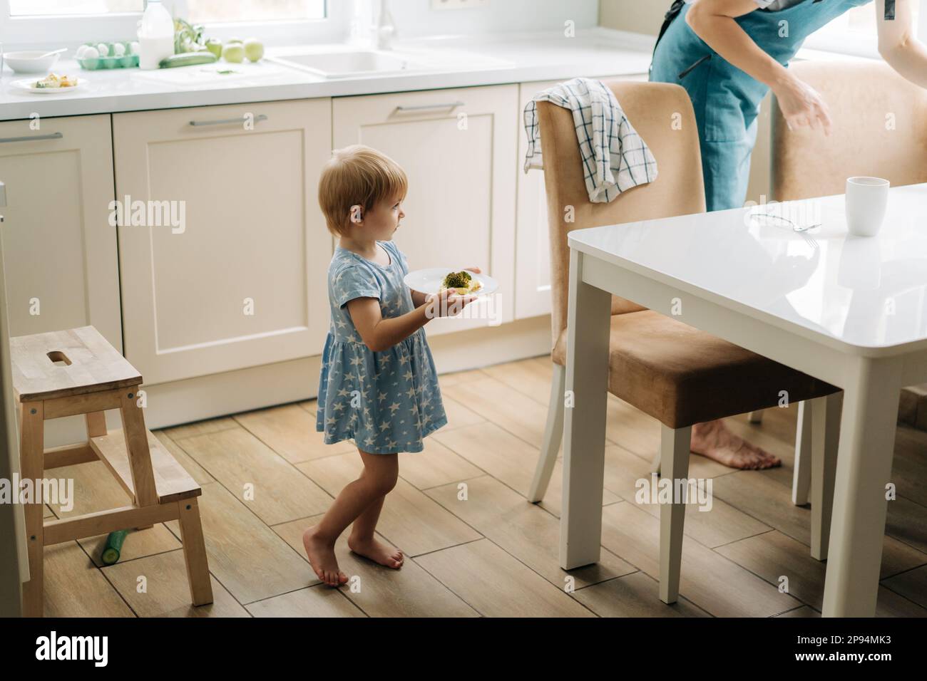 Mom and little daughter are setting the table for dinner at home in the ...