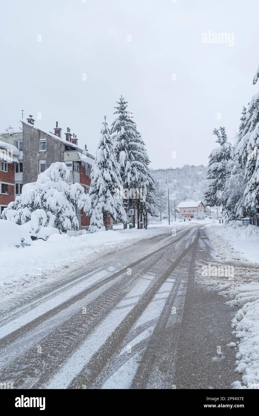 A vertical rural landscape of a road covered in snowy in winter Stock ...
