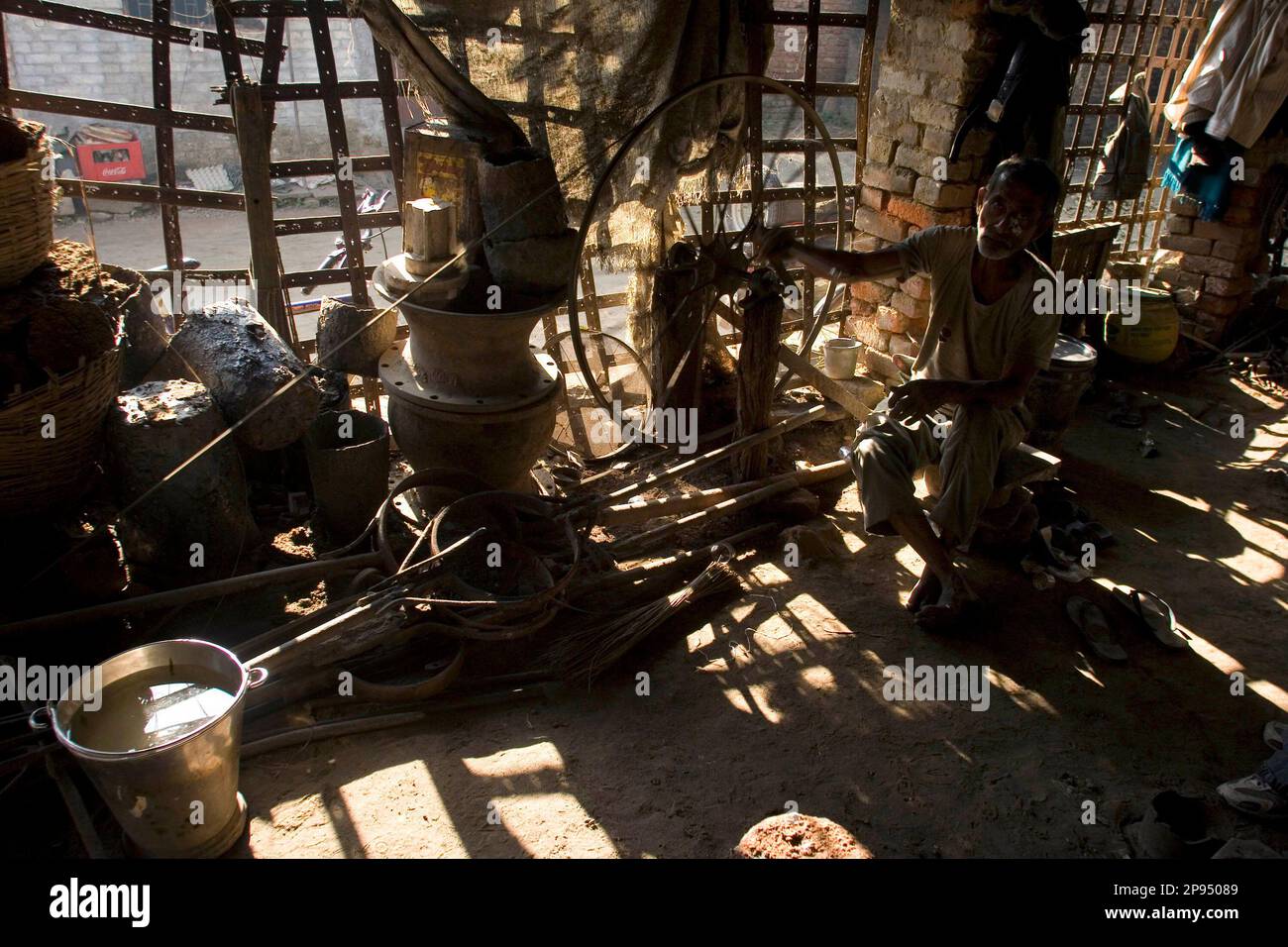 An Indian ironsmith looks on at his workshop in Allahabad, India ...