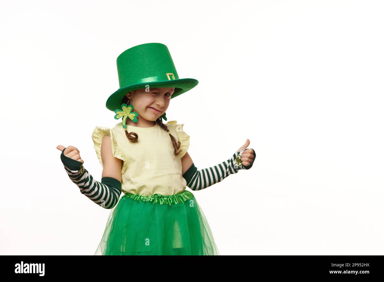 Pretty child girl wearing clover leaf earrings and carnival green hat ...