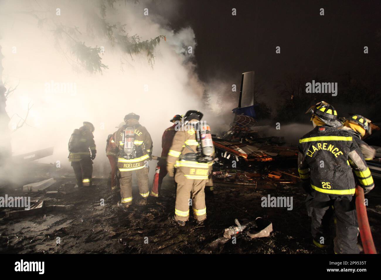Firefighters work to extinguish the fire at the site of the crash of ...
