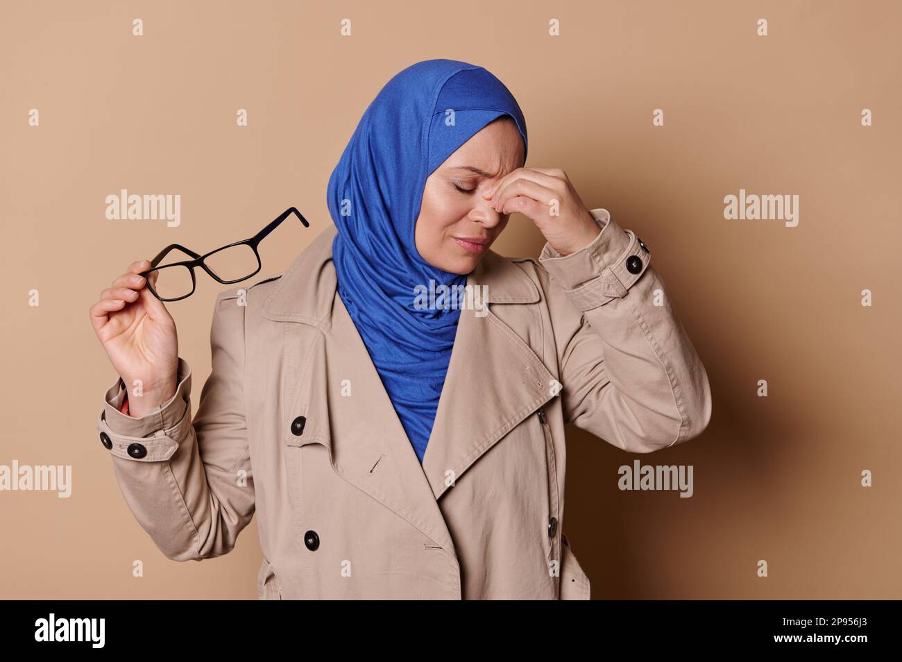 Overworked multitasking Arab Muslim woman in blue hijab and beige ...