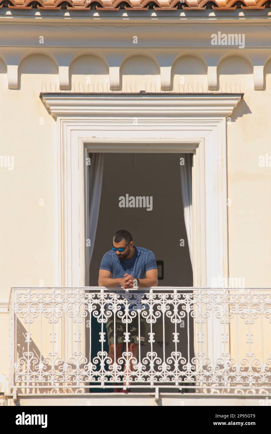 Man, presumably a hotel guest, leaning and looking out from a hotel ...