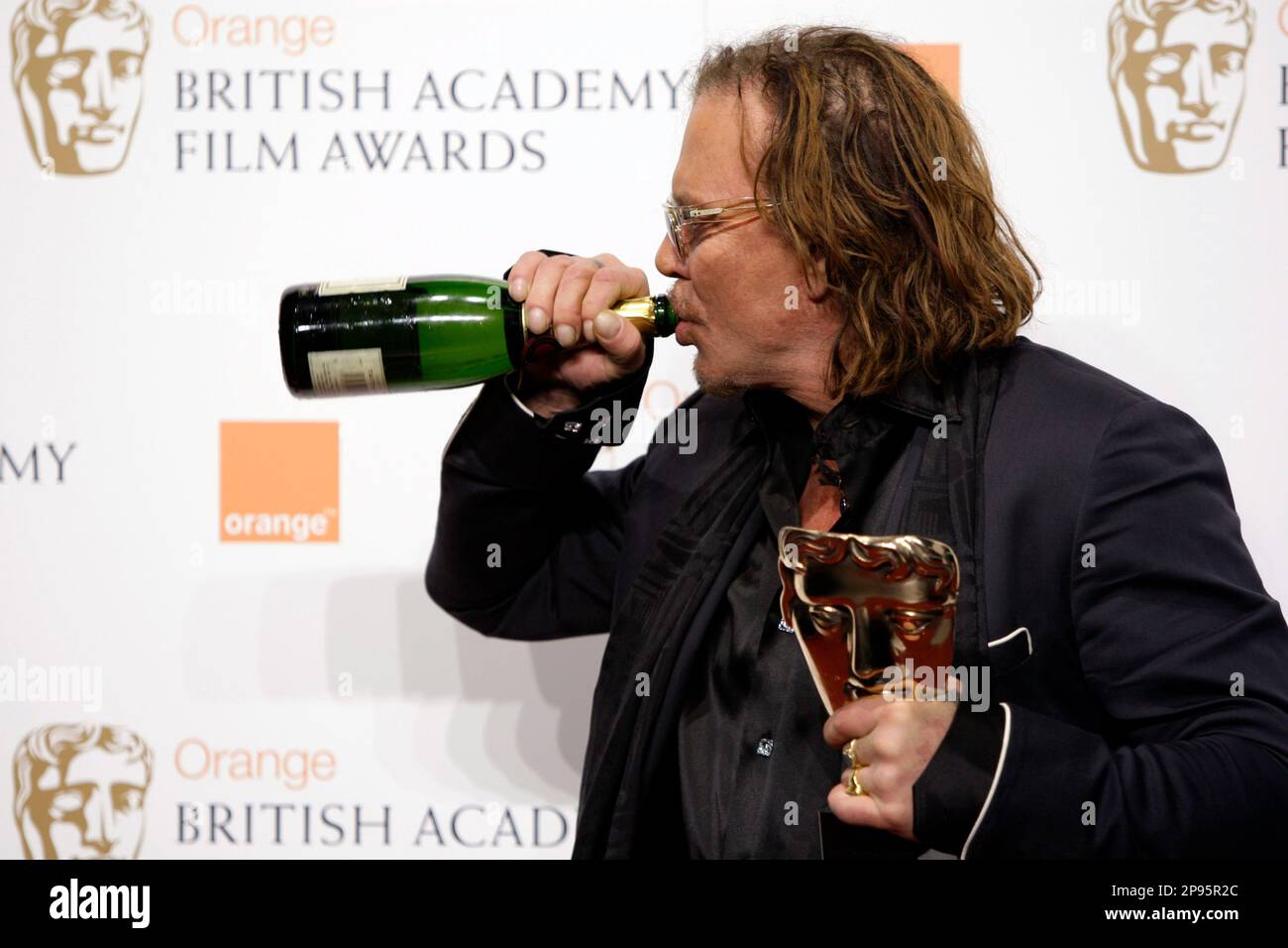 US actor Mickey Rourke drinks from a bottle of champagne as he holds ...