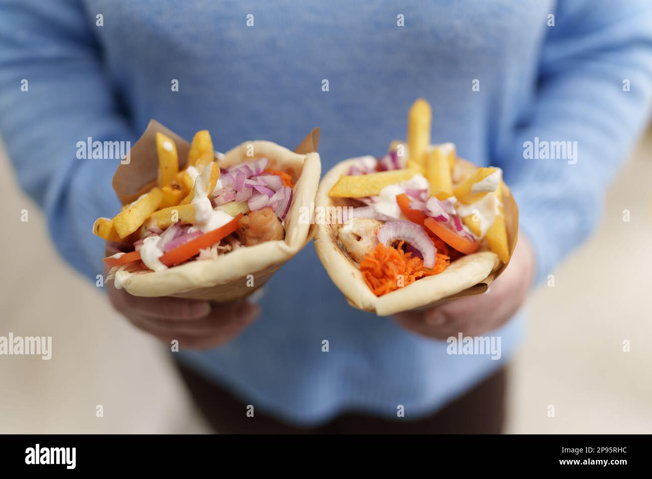 Woman holds pair of gyros in pita bread. Female person brings ...