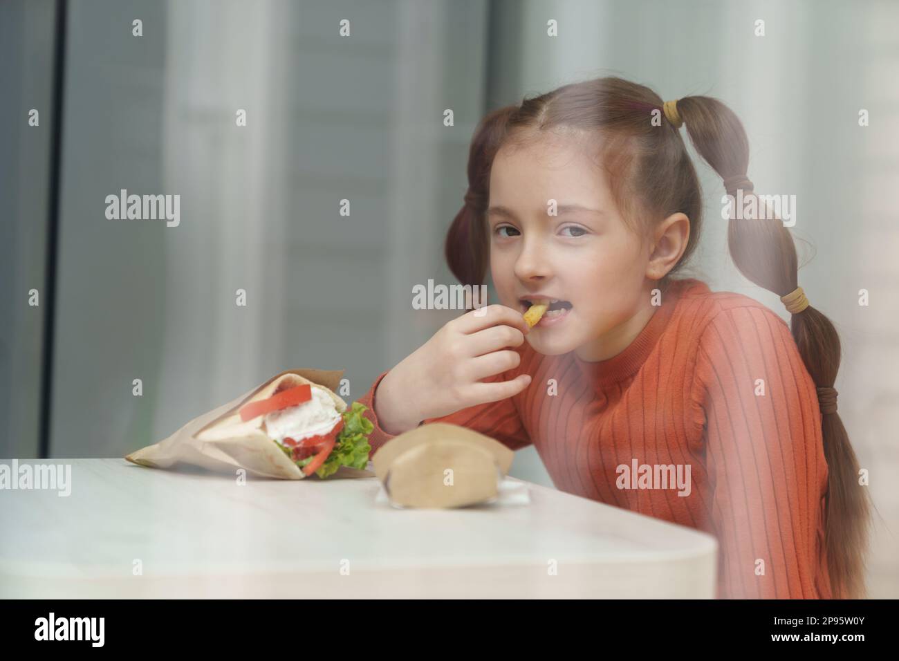 Cute little girl with ponytails eating souvlaki for lunch in Greek ...