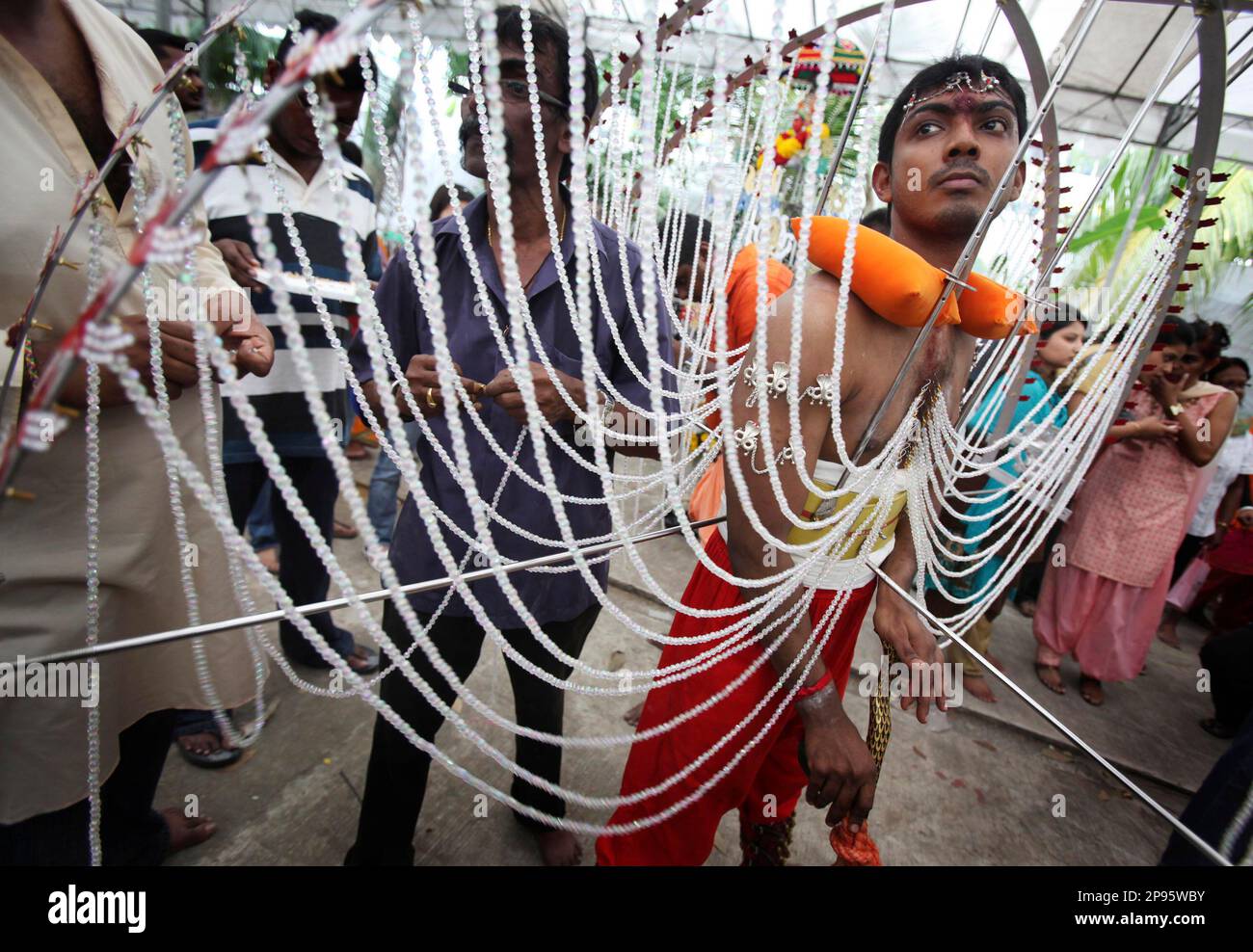 A Hindu devotee carries a Kavadi offering cage as he waits to take part ...