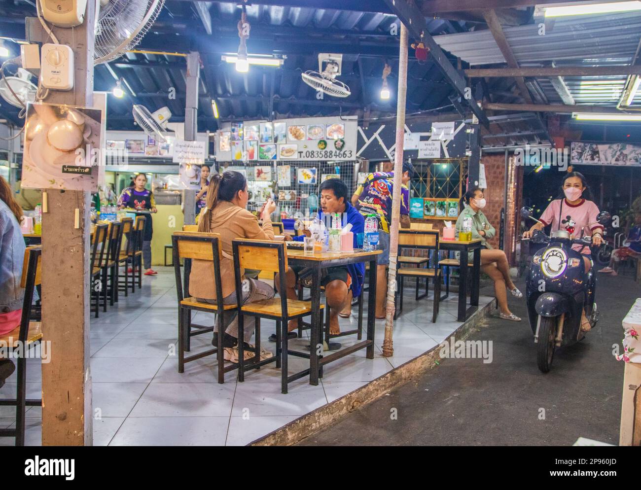 A traditional street restaurant with a narrow passage for scooters in ...