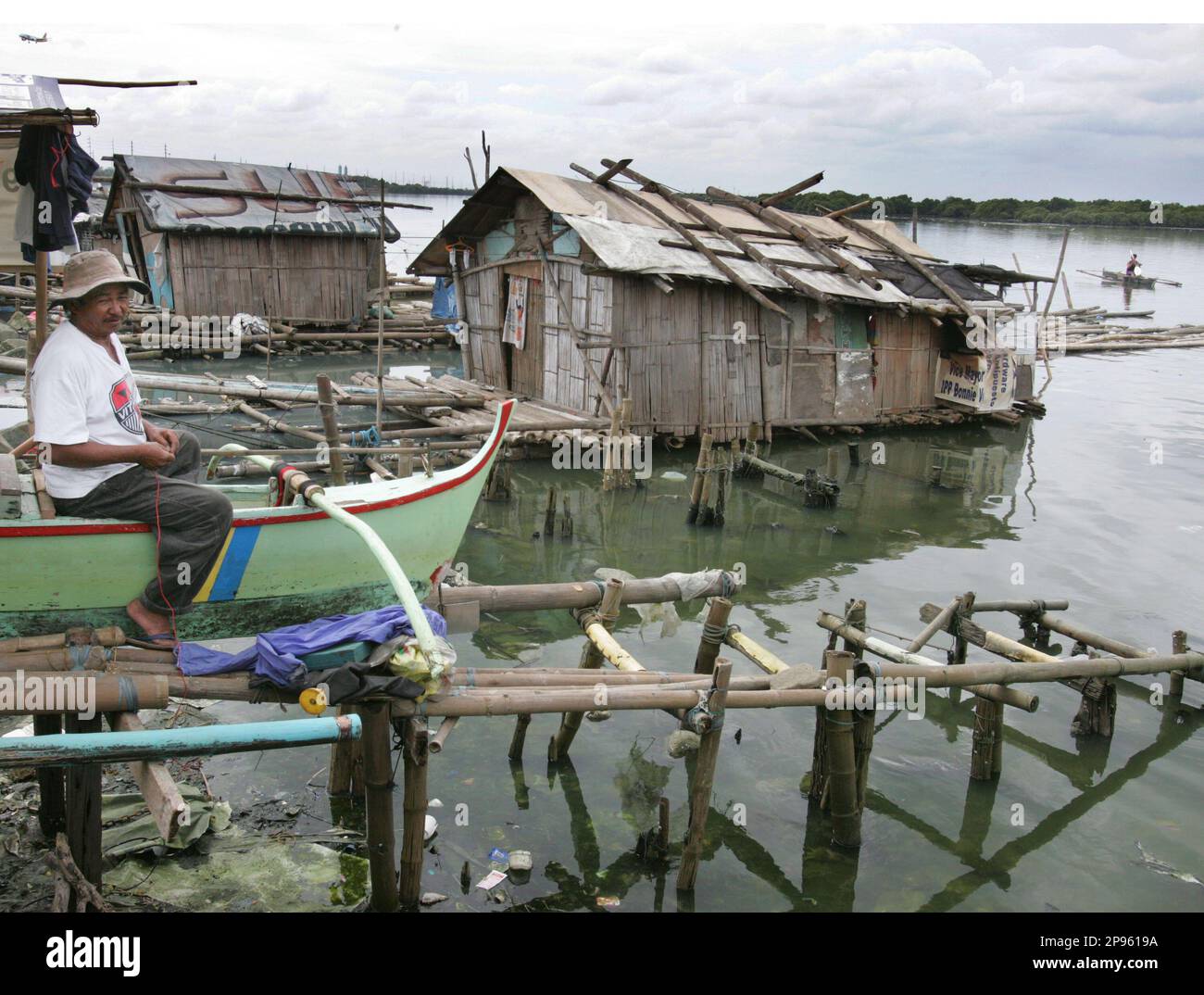 A man sits on his outrigger near houses that were built on rafts ...