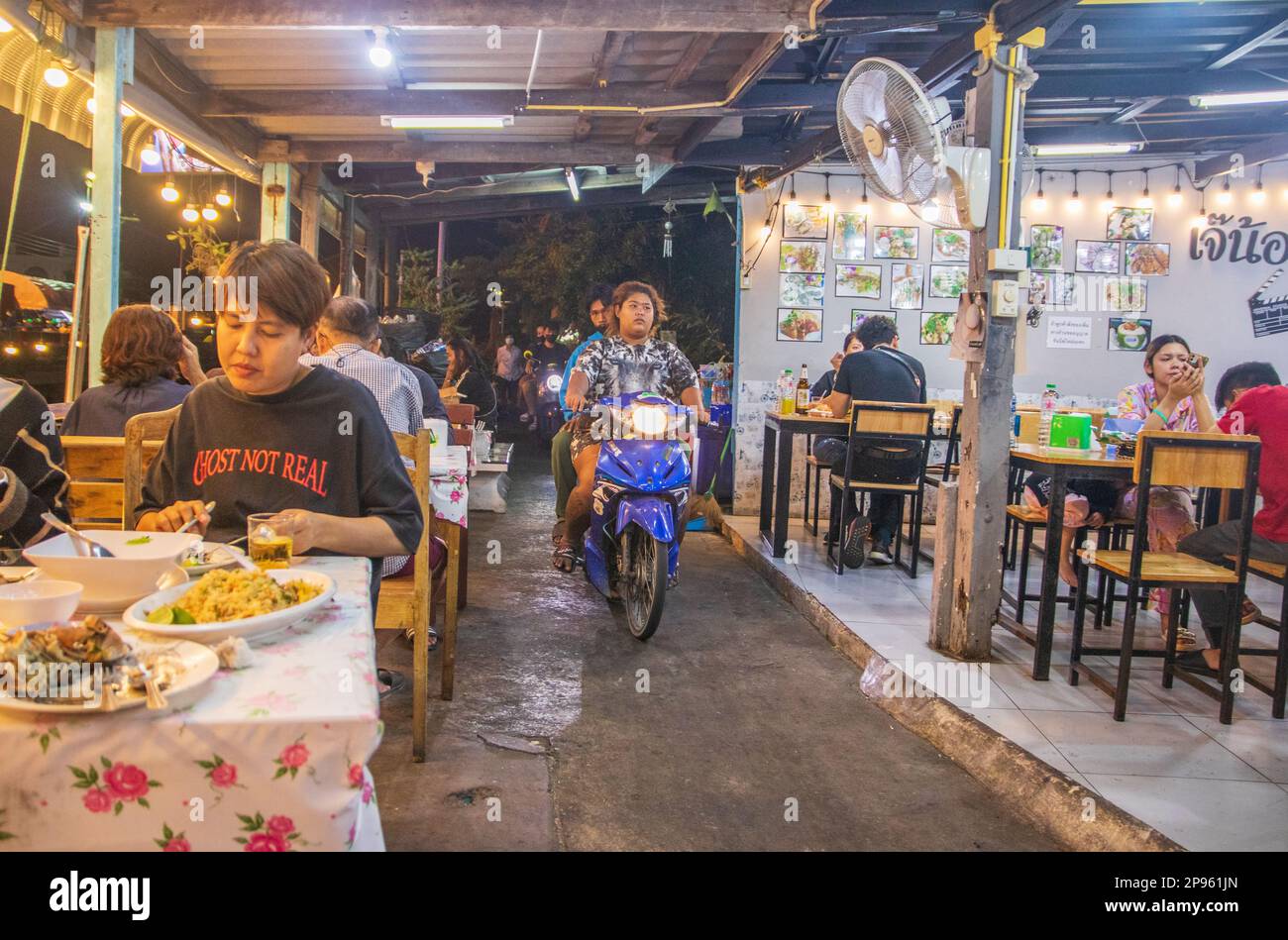 A traditional street restaurant with a narrow passage for scooters in ...