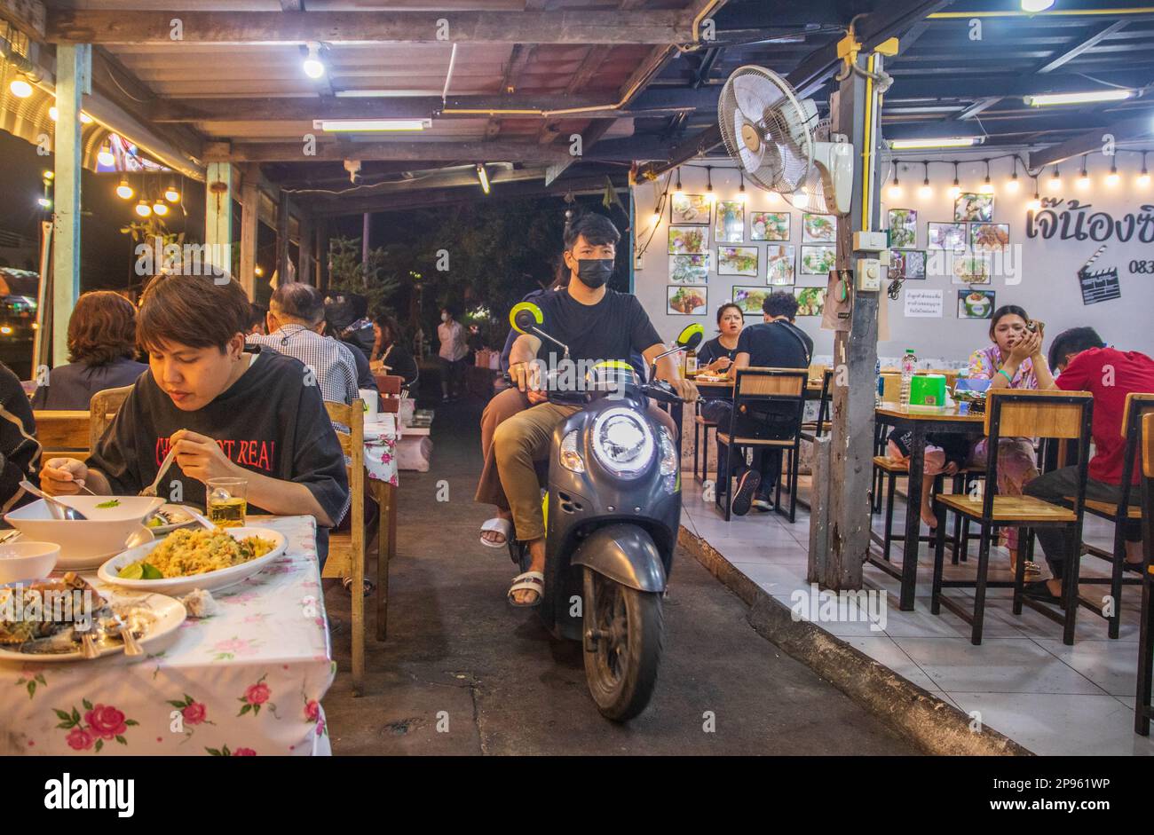 A traditional street restaurant with a narrow passage for scooters in ...