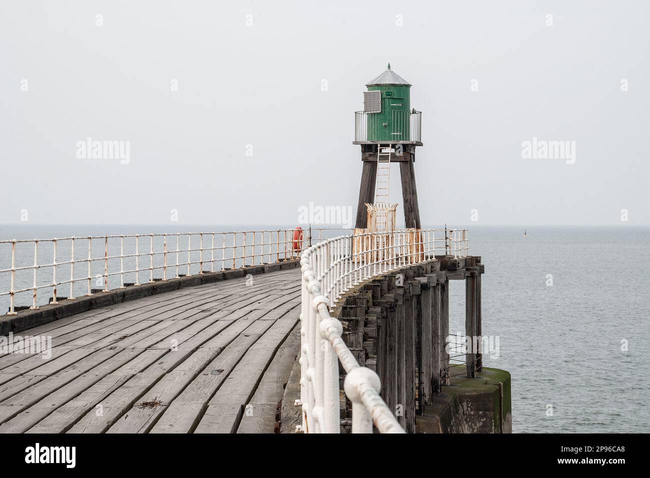The green painted beacon at the end of the curved pier at Whitby. Red ...