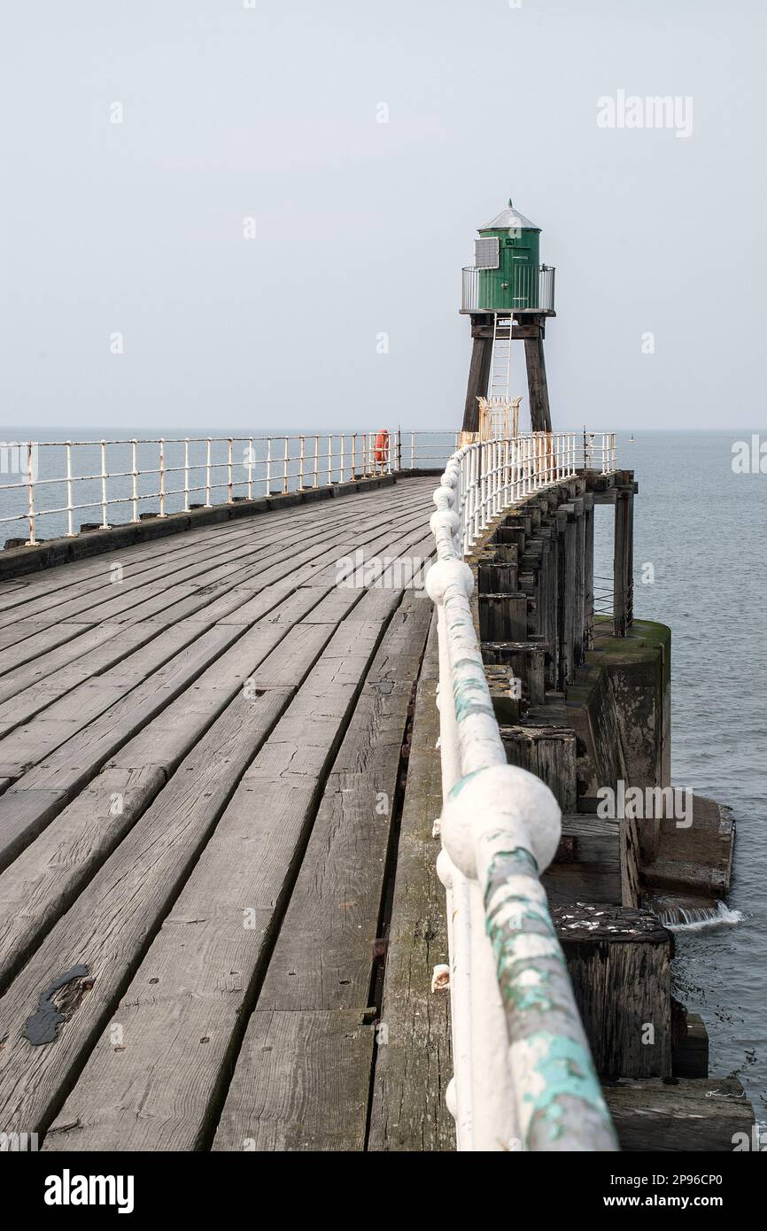The green painted beacon at the end of the curved pier at Whitby. Red ...