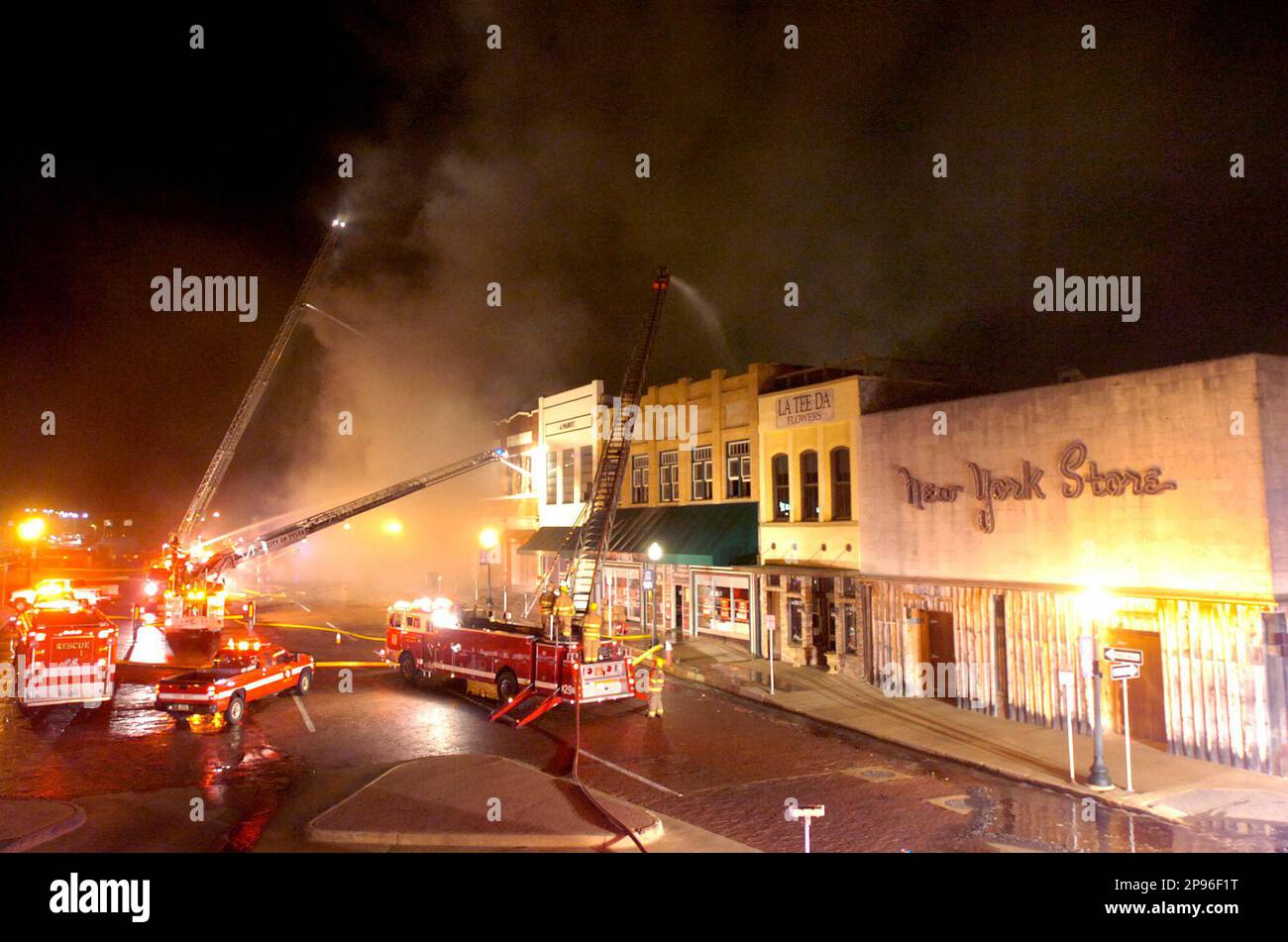 Fire trucks fill the street as smoke fills the sky from a building fire ...