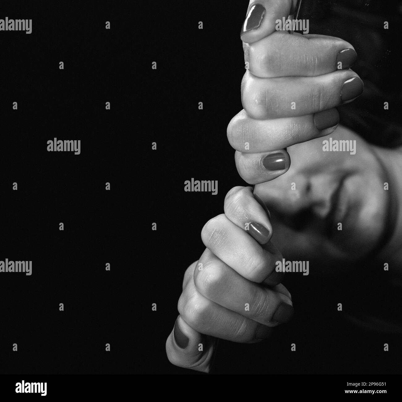 The hands holding a mirror reflecting a woman in grayscale with copy ...