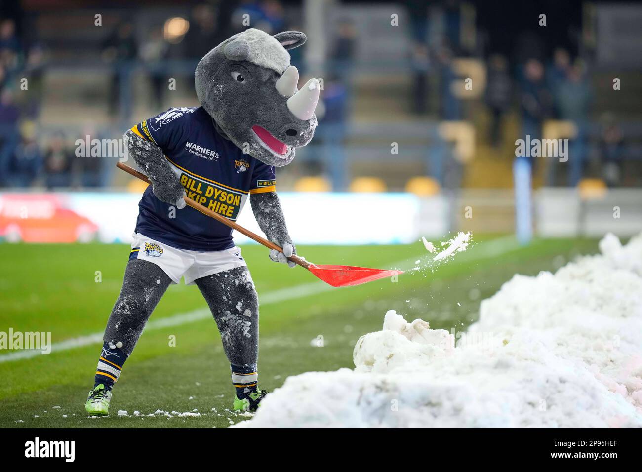 Leeds Rhinos mascot Ronnie Rhino clears snow from the side of the pitch ...