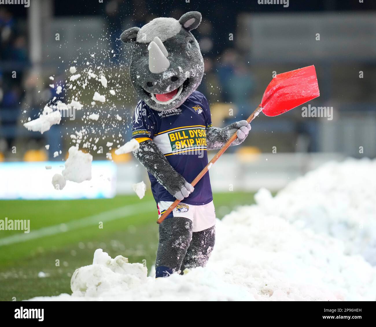 Leeds Rhinos mascot Ronnie Rhino clears snow from the side of the pitch ...