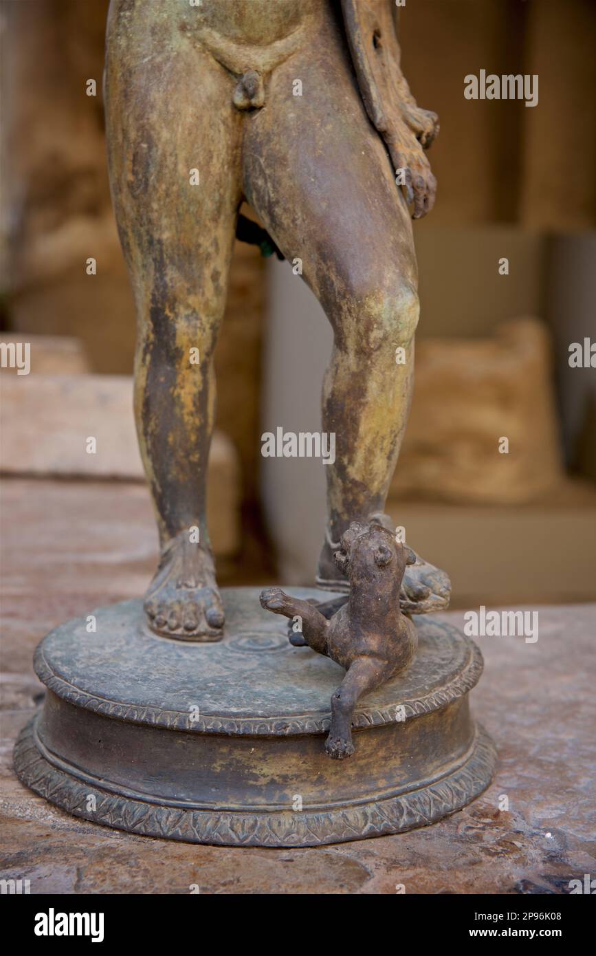 Detail of lower half of male bronze figurine standing on a pacified ...