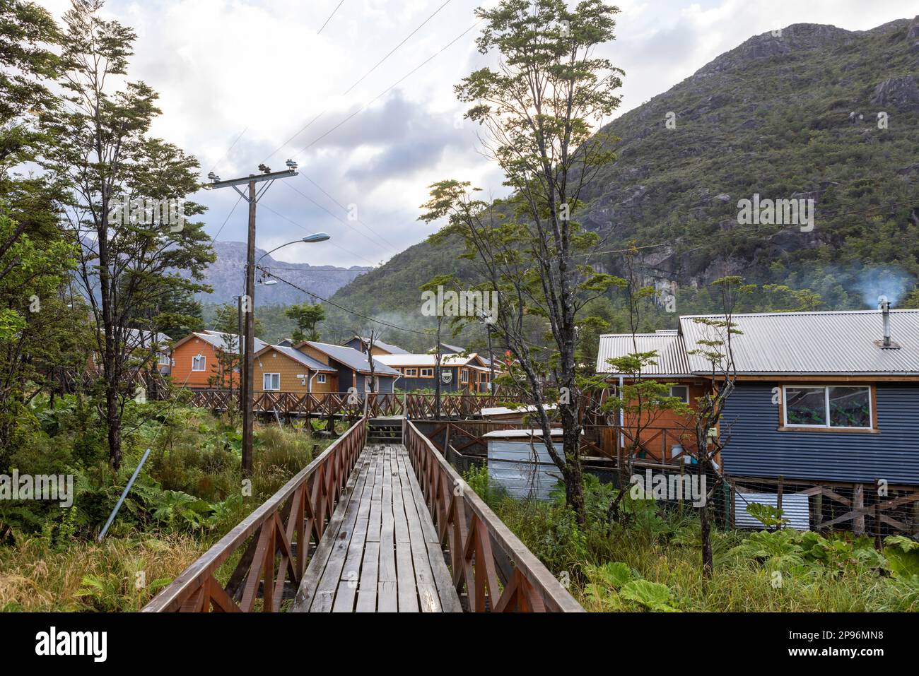 Small colorful houses and nalca plants along the wooden paths of Tortel ...