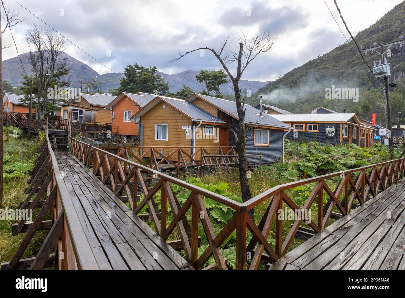 Small colorful houses and nalca plants along the wooden paths of Tortel ...