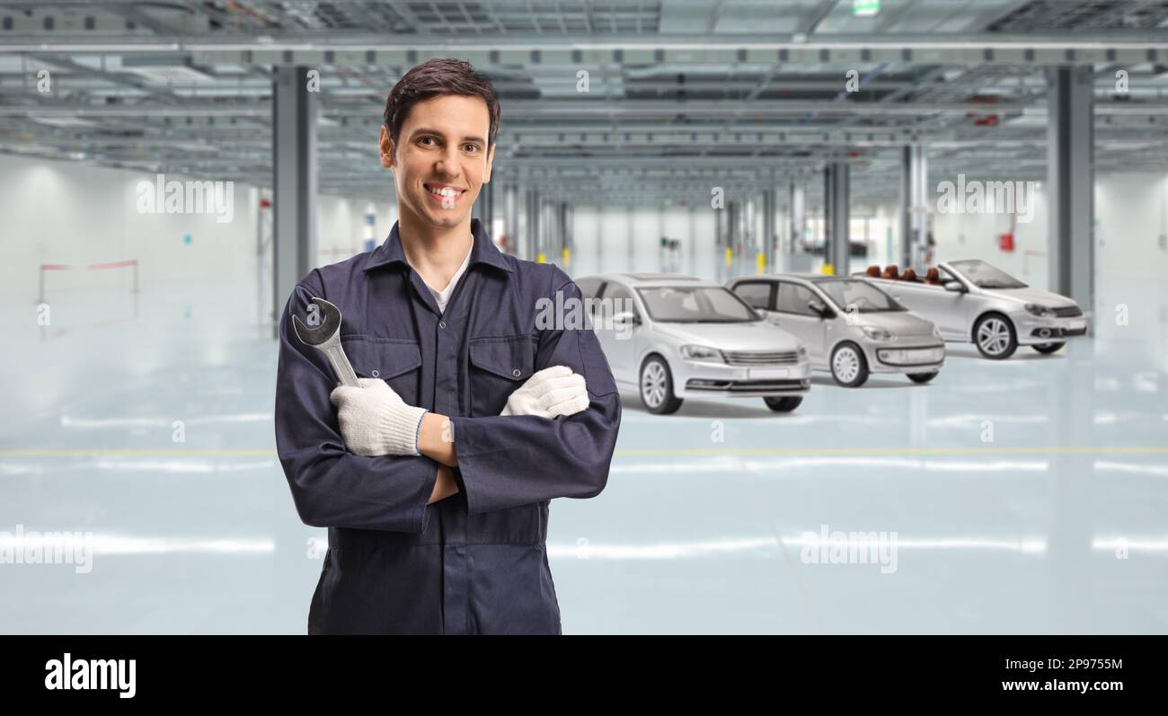 Factory worker holding a wrench and posing in a garage with cars Stock ...