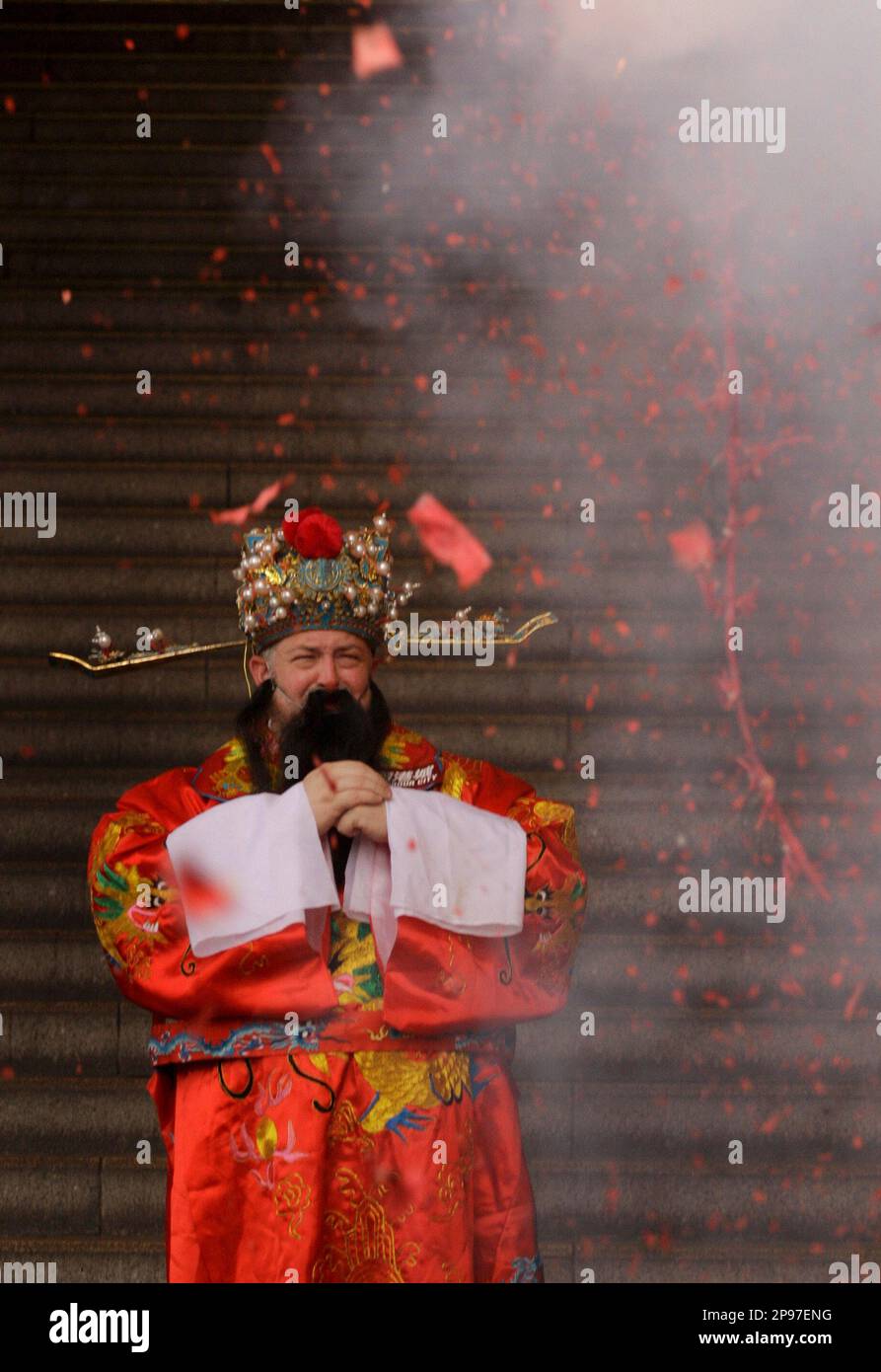A man dressed like the Chinese God of Fortune greets visitors behind a ...