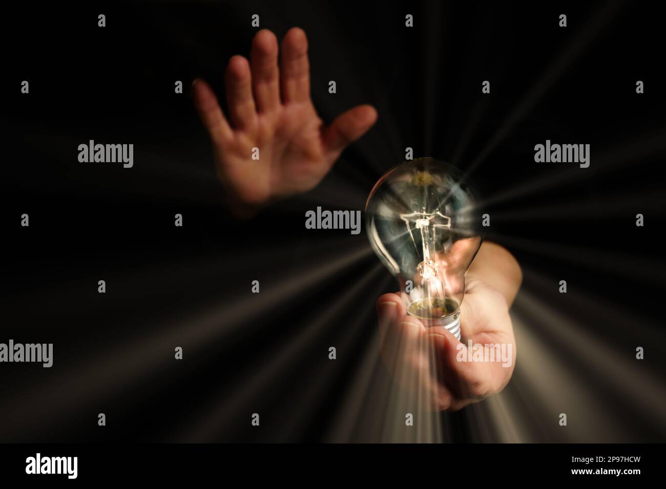man holding in his hands a lighted light bulb with rays of light on a ...