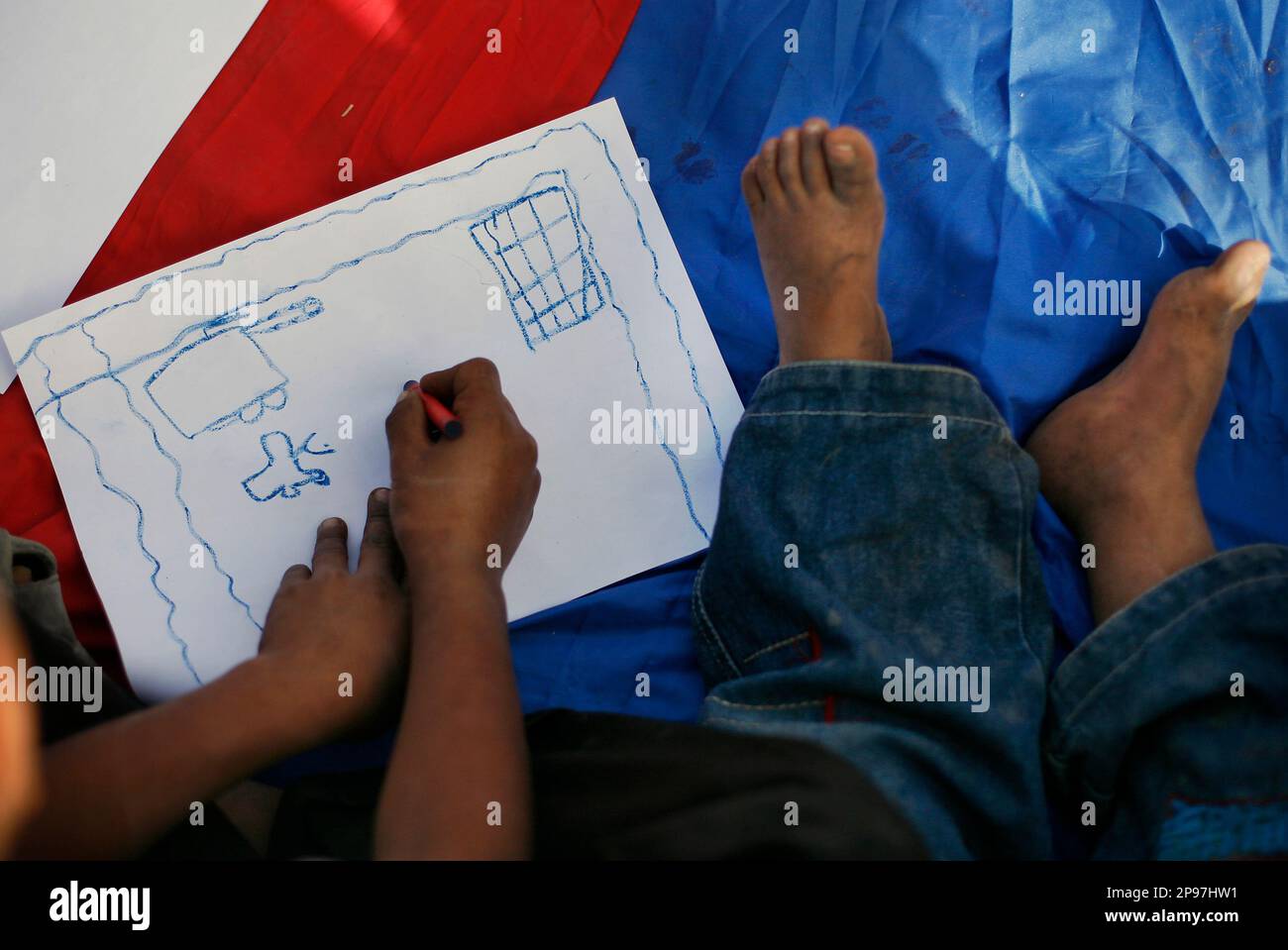 A Palestinian child draws a tank aiming towards a house on a sheet of ...