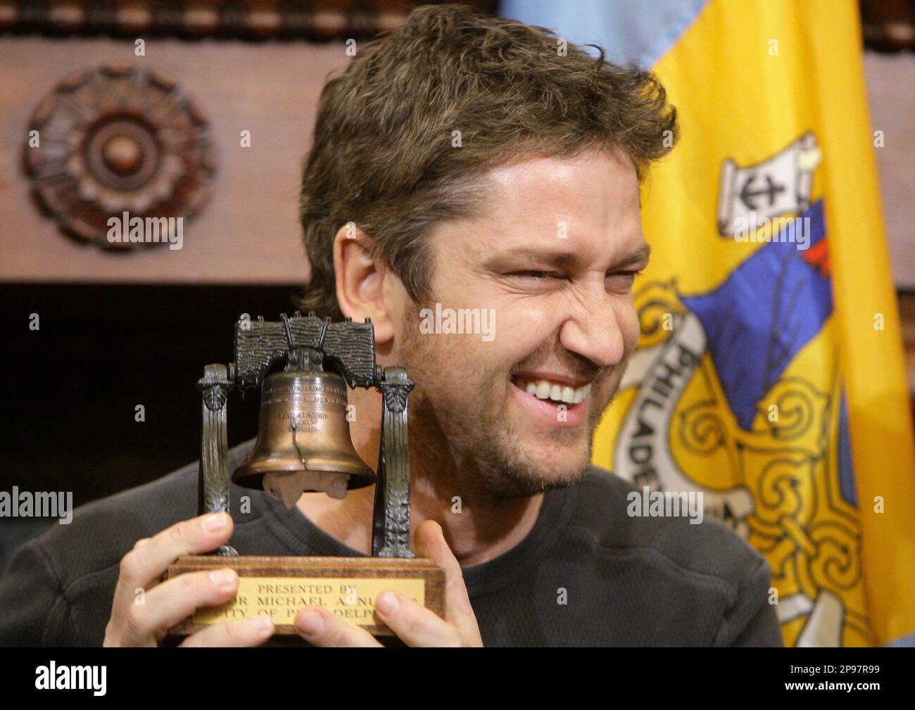 Actor Gerard Butler displays a model of the Liberty Bell during a news ...