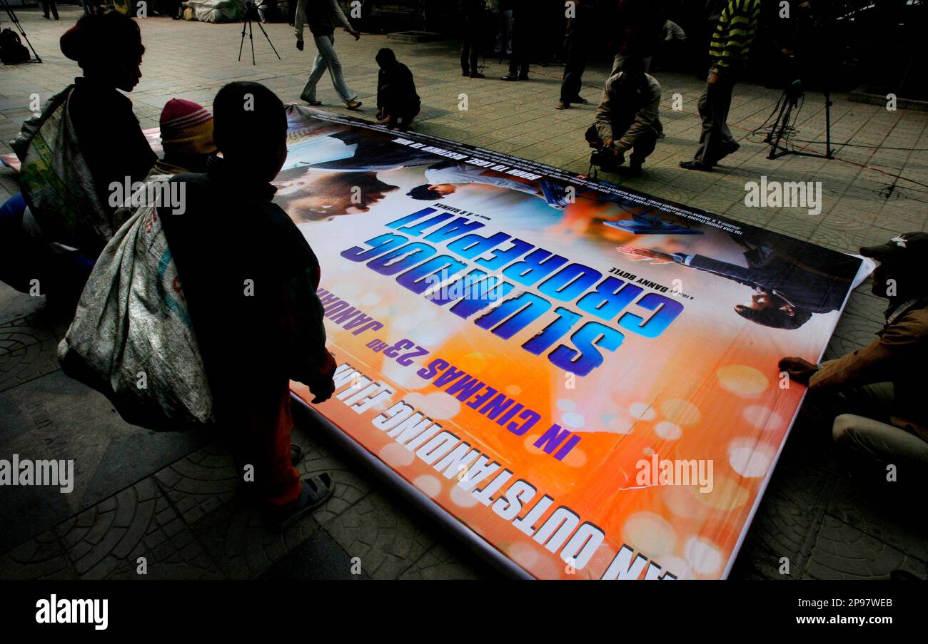Rag picker boys watch workers prepare a billboard of "Slumdog Crorepati ...