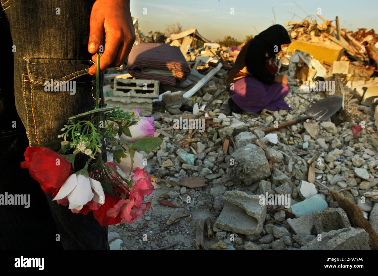 A Palestinian youth holds fake flowers that he salvaged from the rubble ...