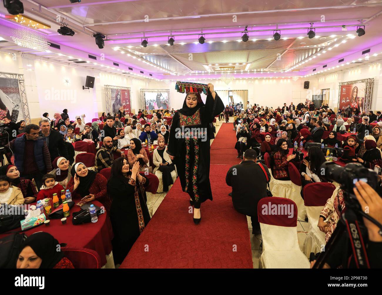 A Palestinian young lady wearing traditional embroidered dress takes ...