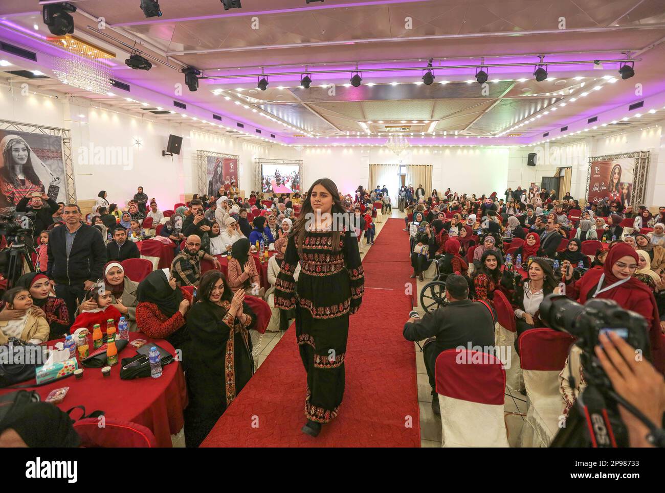 A Palestinian young lady wearing traditional embroidered dress takes ...