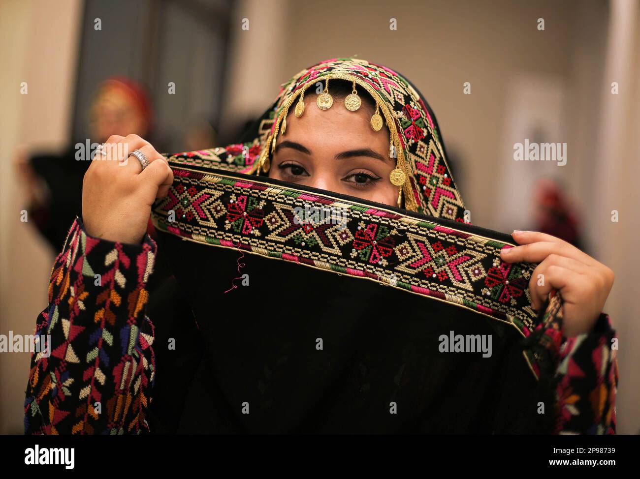A Palestinian young lady wearing a traditional embroidered dress takes ...