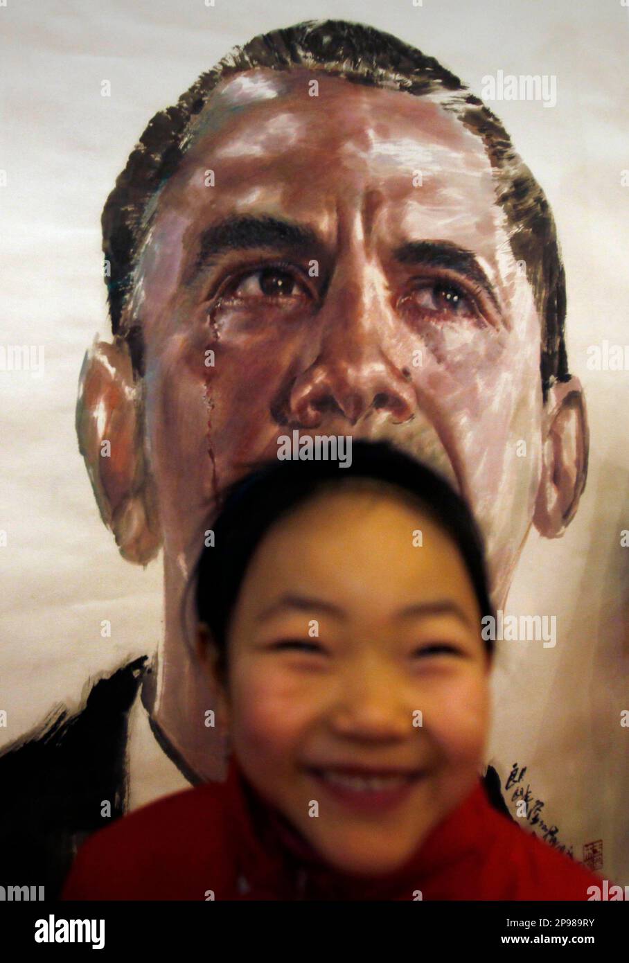 A Chinese girl smiles as she poses for a snapshot with a painting ...