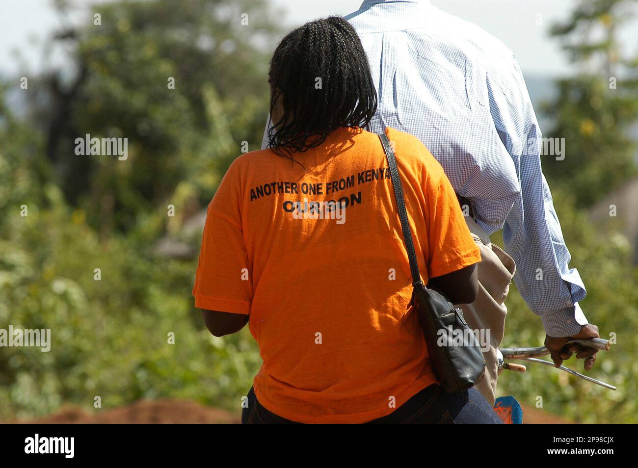 A woman sits on the back of a bicycle in the village of Kogelo, Kenya ...