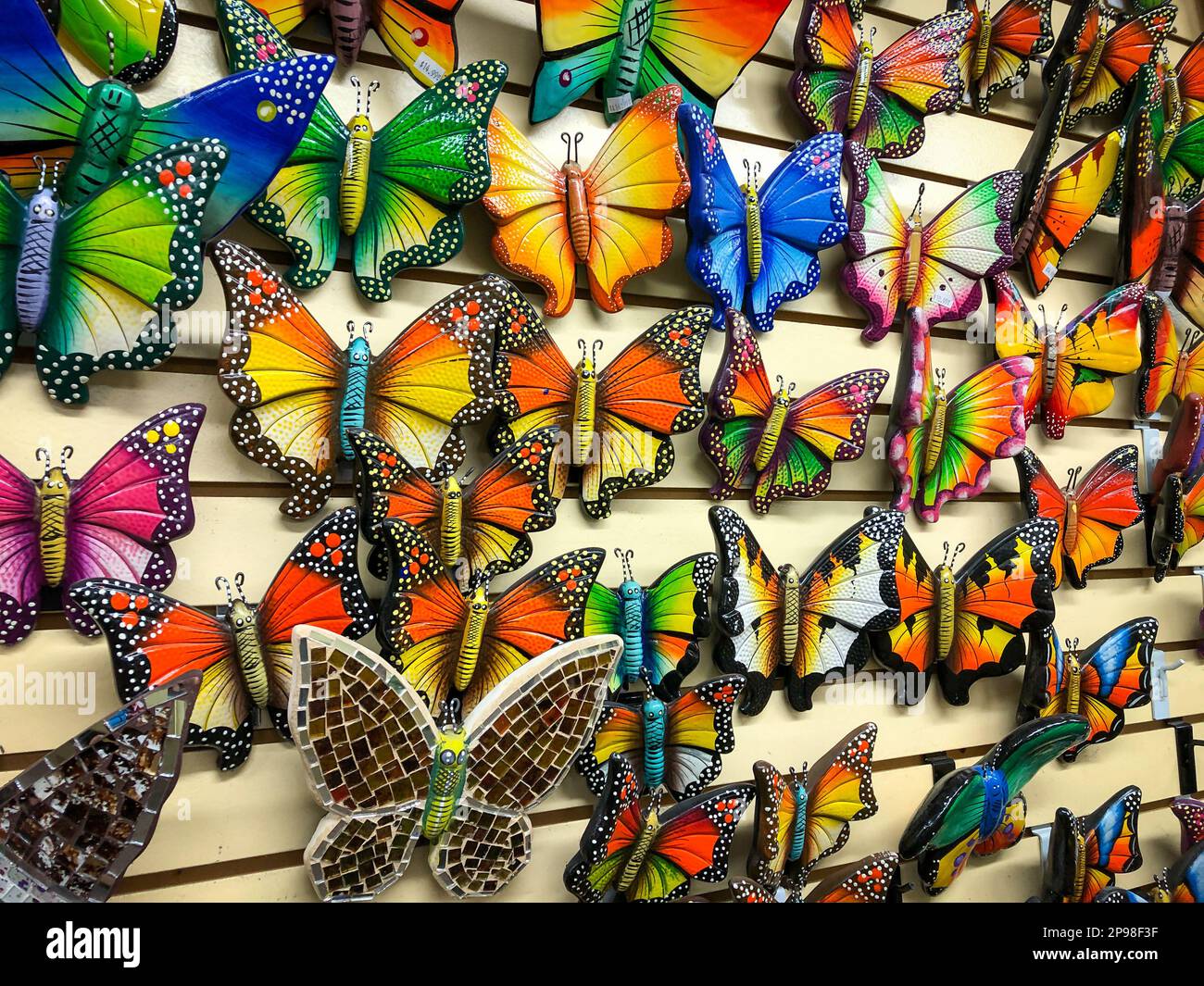 Many colorful painted ceramic butterflies hanging on a wall display and ...