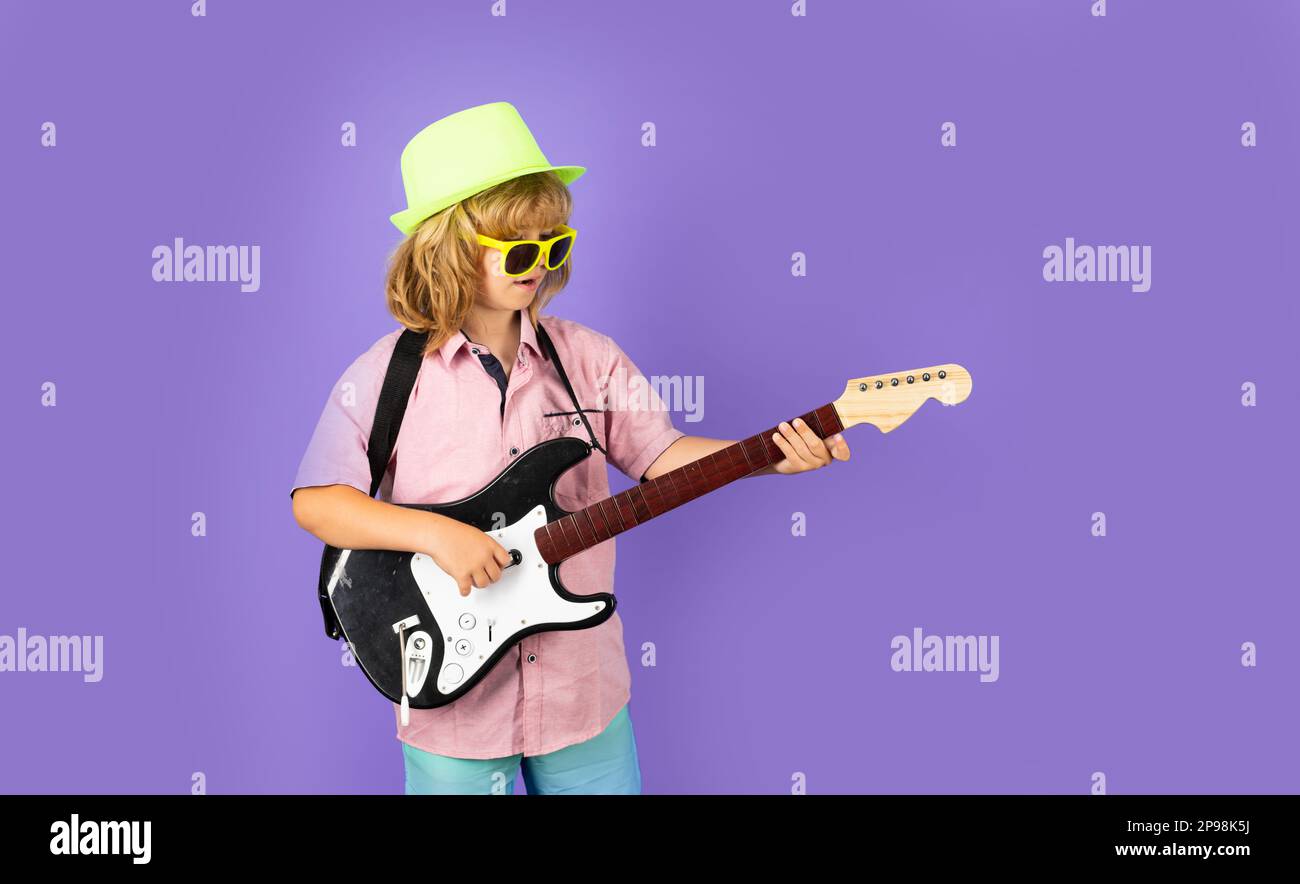 Child musician playing the guitar like a rockstar on studio background ...