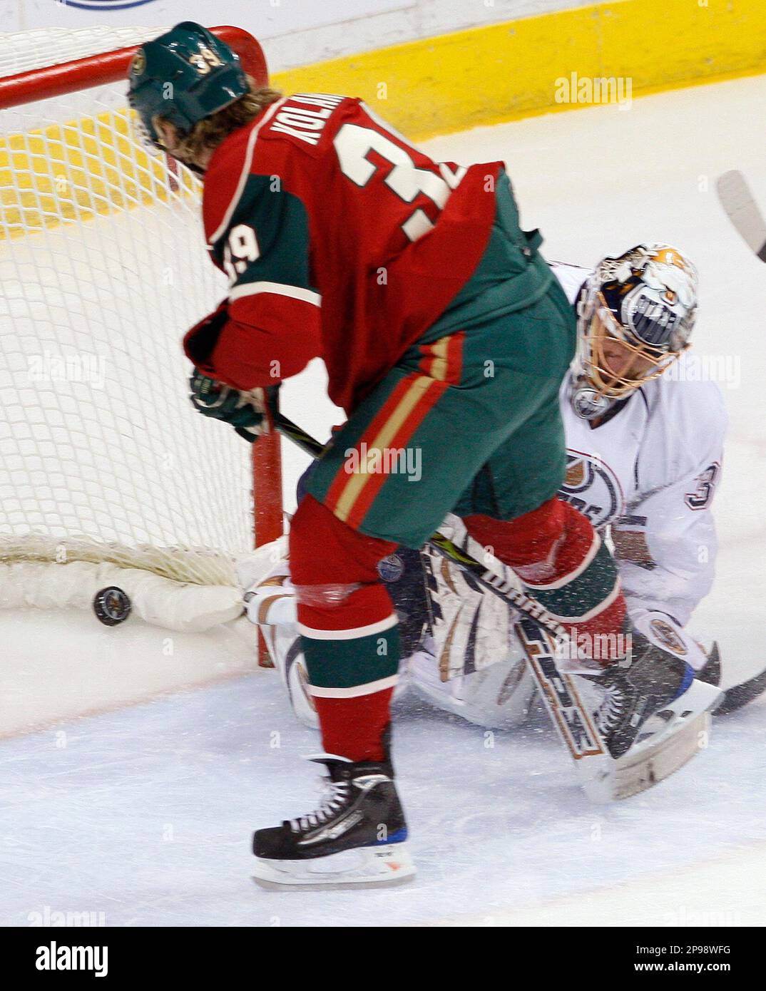 Minnesota Wild center Krystofer Kolanos, left, gets the puck past ...