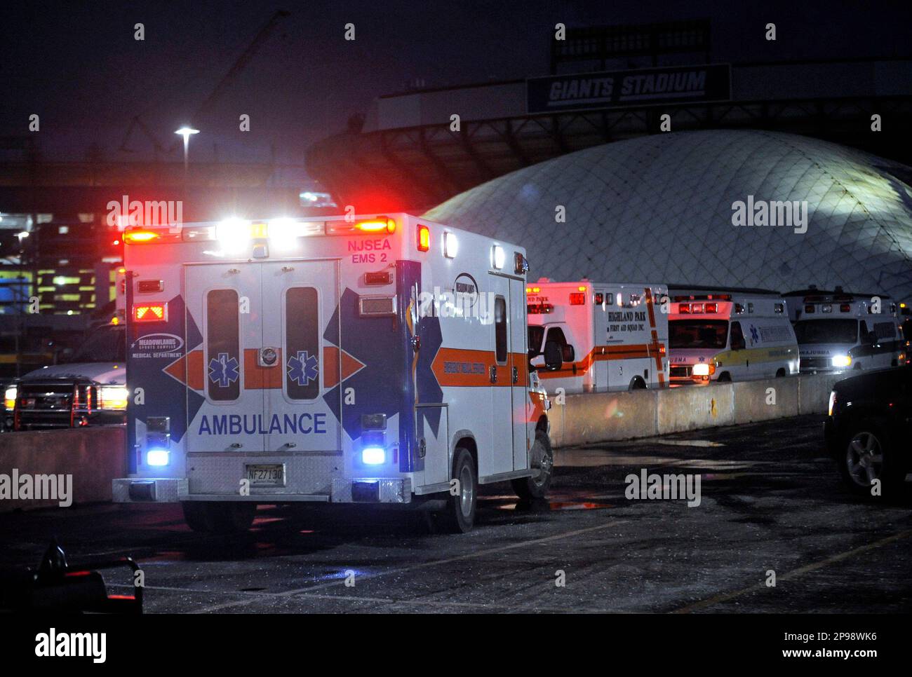 Ambulances and EMS crews gather at a staging area in a parking lot ...