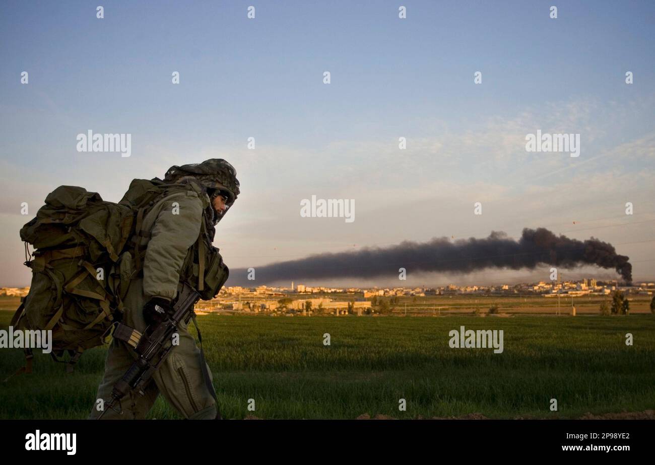 An Israeli soldier carries his gear at a staging area near the border ...