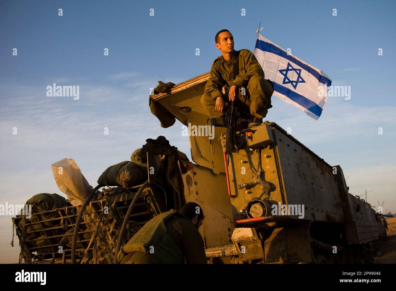 An Israeli soldier sits atop of an armored vehicle at a staging area ...